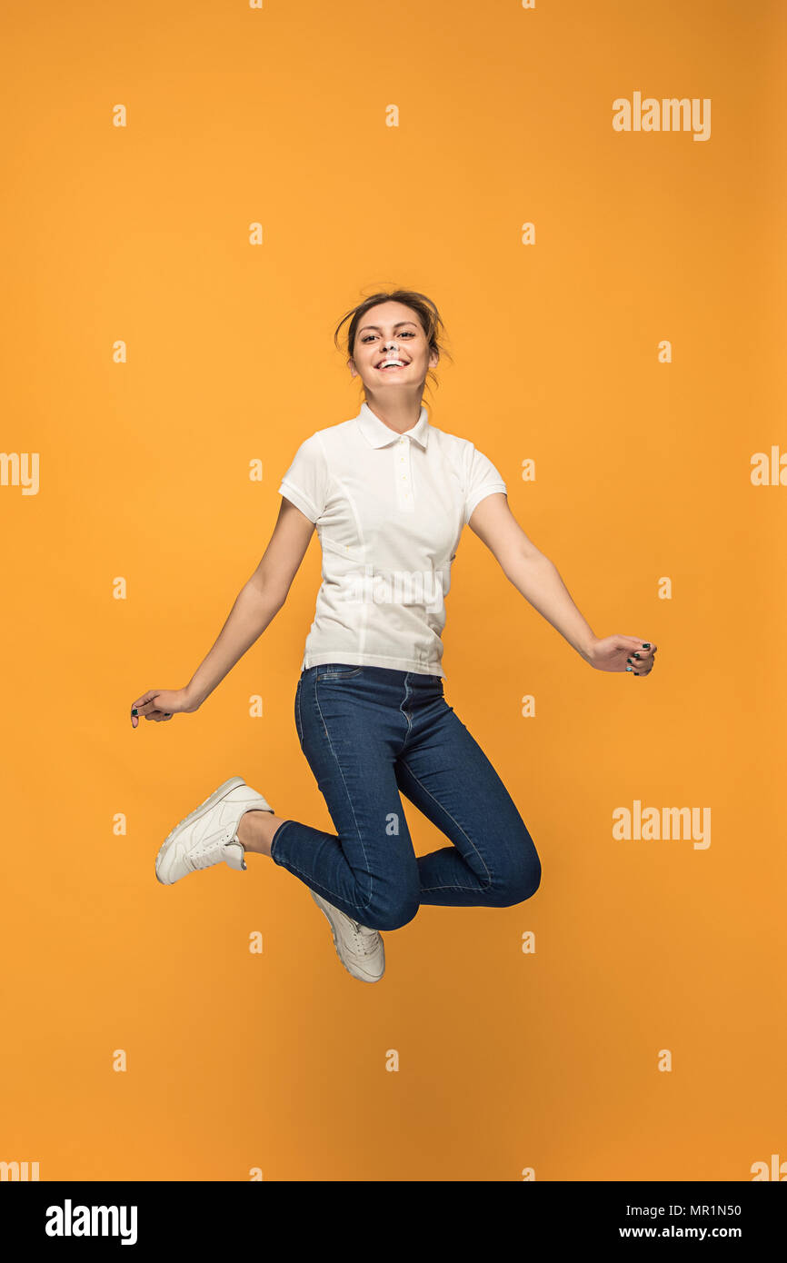 Freedom in moving. Pretty young woman jumping against orange background ...