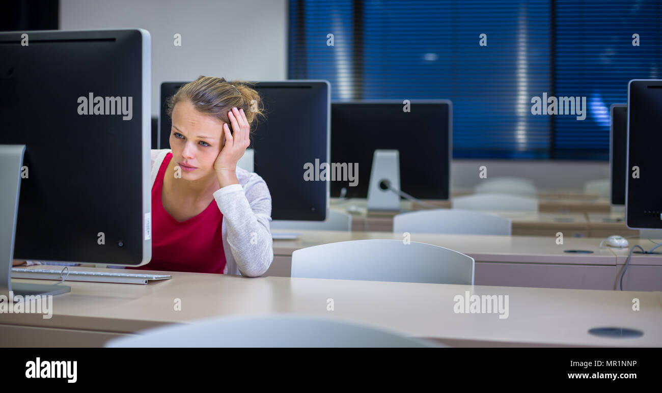 Pretty, young female college student using a desktop computer/pc in a ...