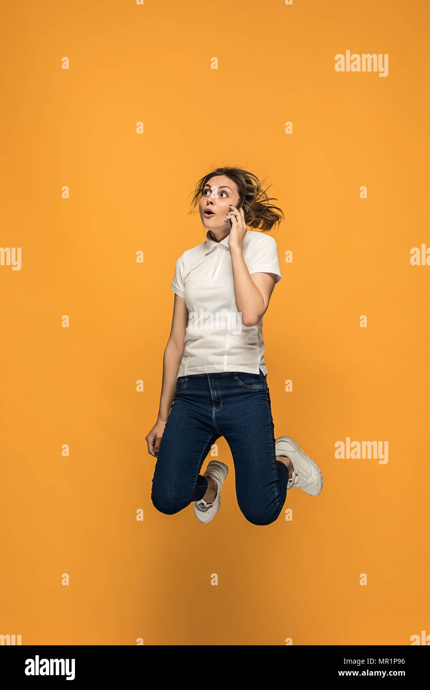 Full length of pretty young woman with mobile phone while jumping Stock ...