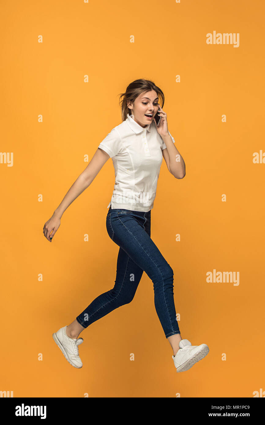 Full length of pretty young woman with mobile phone while jumping Stock ...