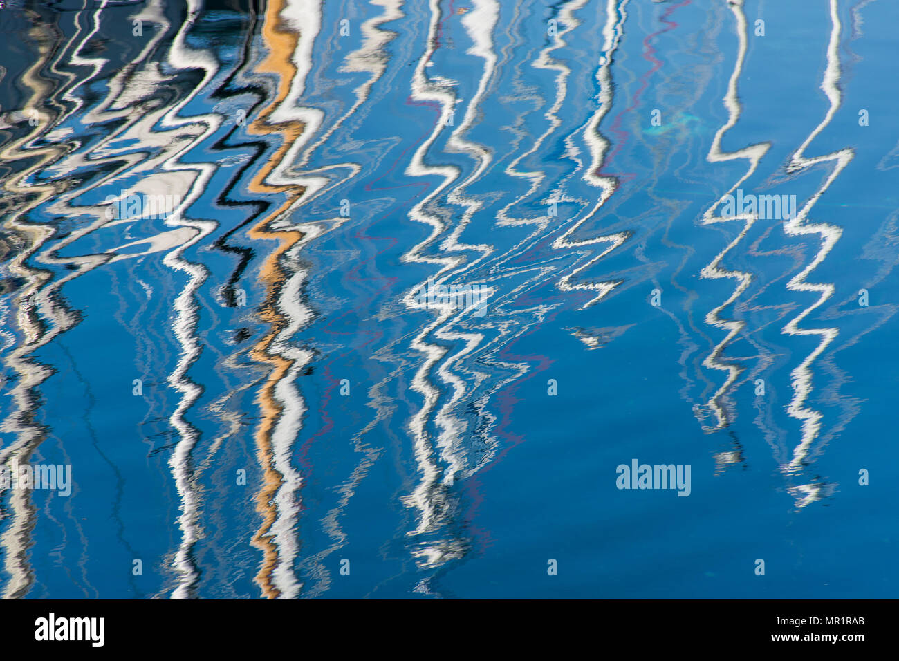Abstract Reflection of colorful sailboats masts on a rippled water ...