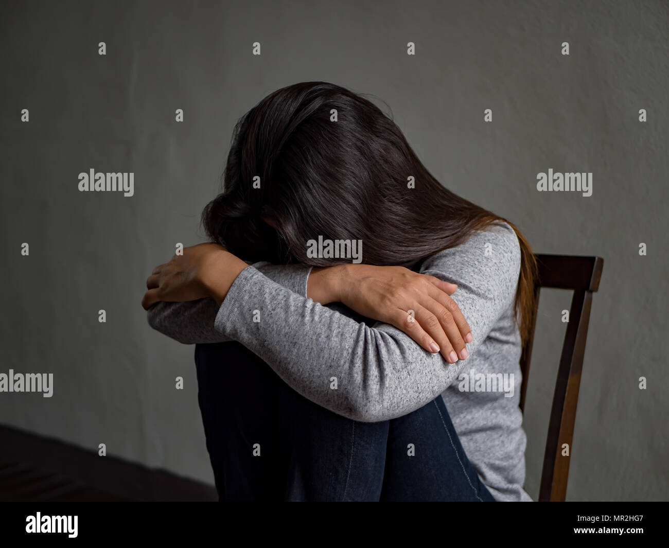 Depressed woman sitting on a chair in dark room at home. Lonly , sad ...