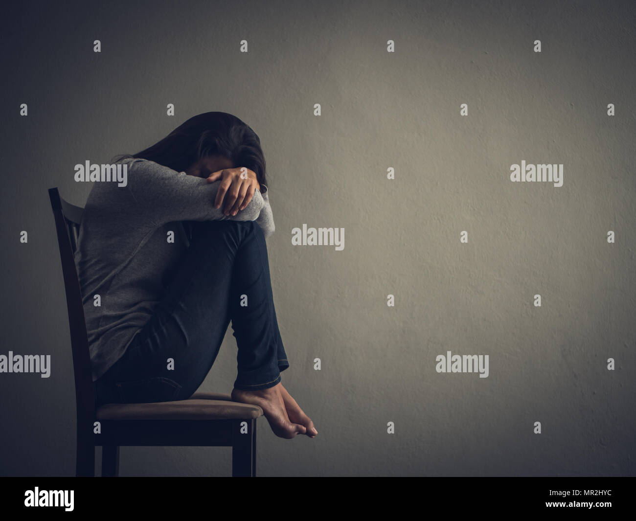 Depressed woman sitting on a chair in dark room at home. Lonly , sad ...