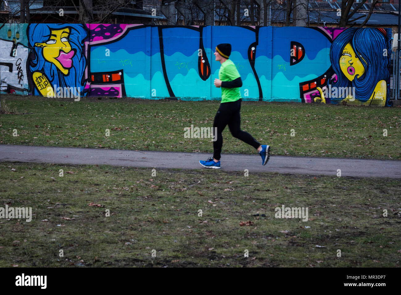 A jogger runs past graffiti in a park in Berlin, Germany Stock Photo ...