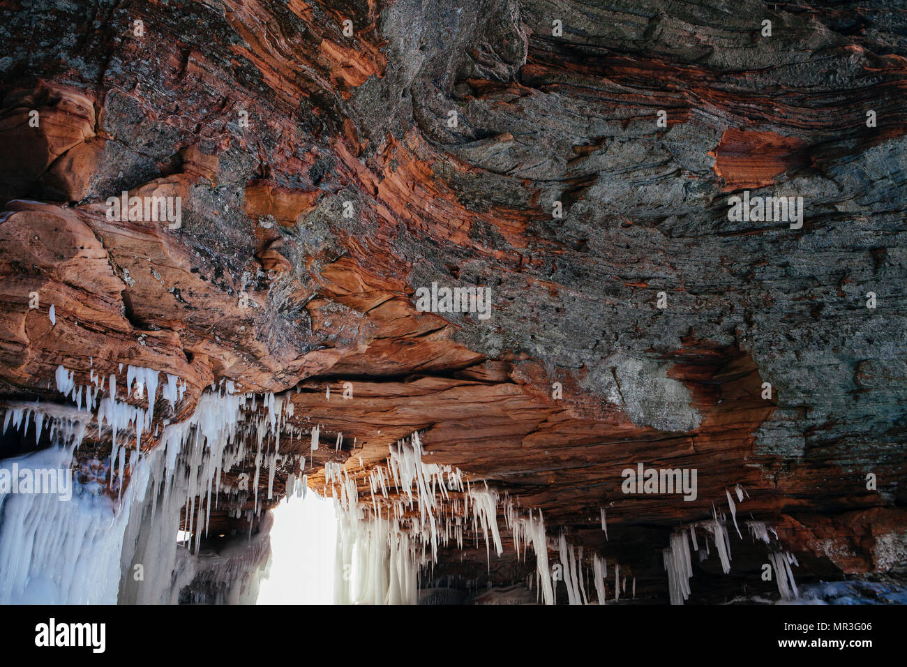 Red rocks are ice covered along the shoreline of the Apostle Islands ...
