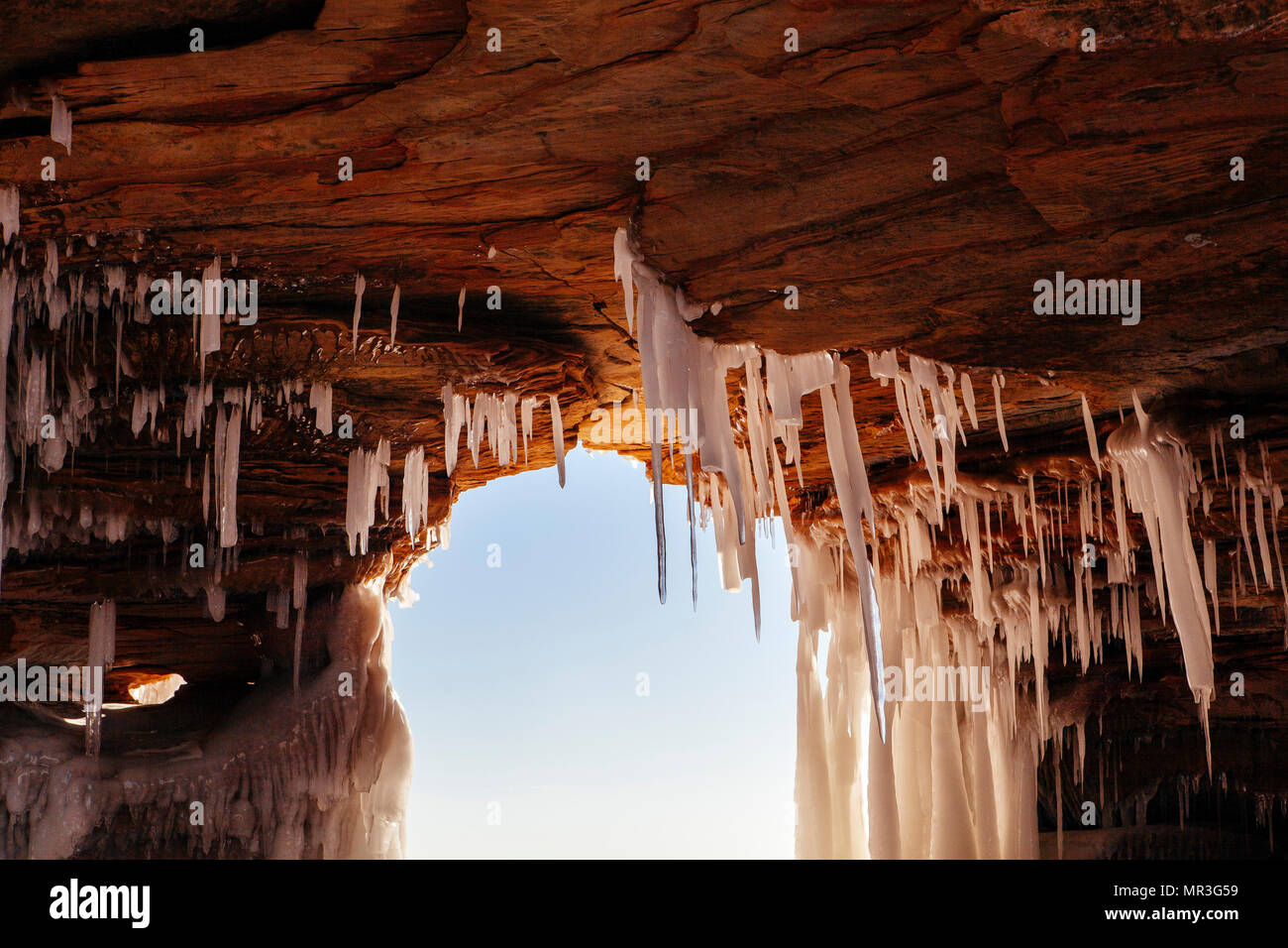 Red rocks are ice covered along the shoreline of the Apostle Islands ...