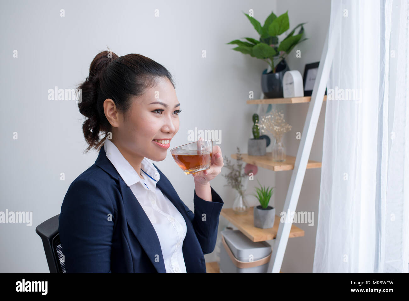 Beautiful mature woman drinking a cup of tea in her office. (with copy ...