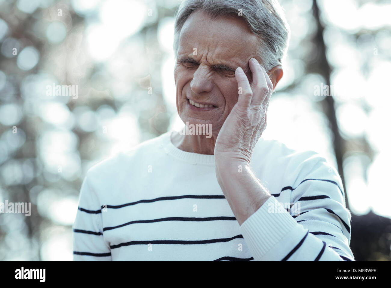 Elderly man making face from pain Stock Photo - Alamy