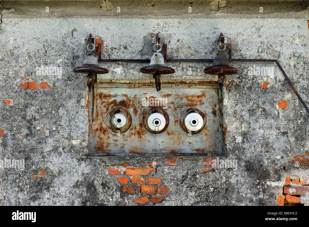Old, rusty electric power line and fuses on an old, ruined brick wall ...