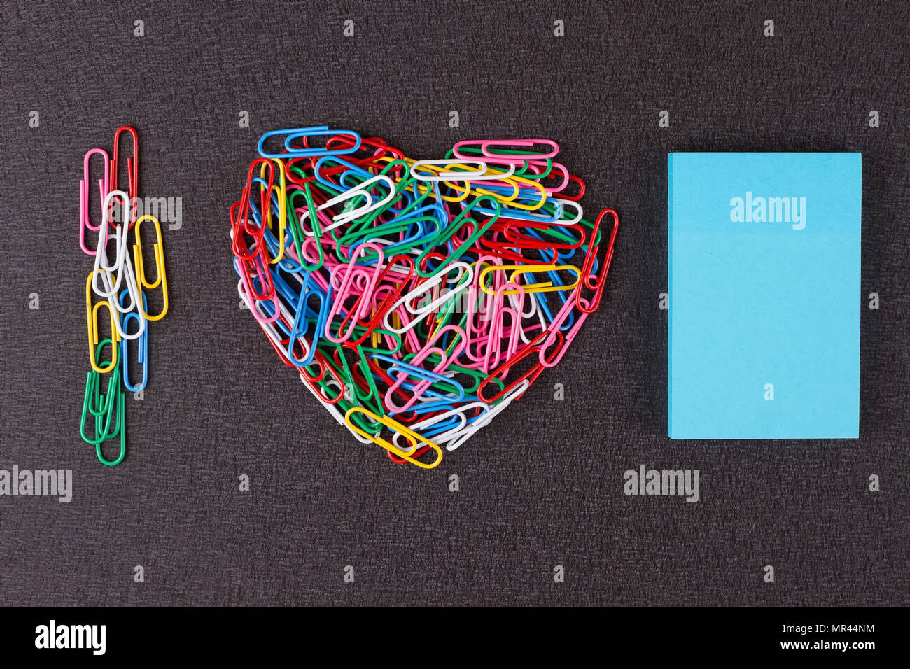 Variety of color paper clips arranged in heart shape on black ...