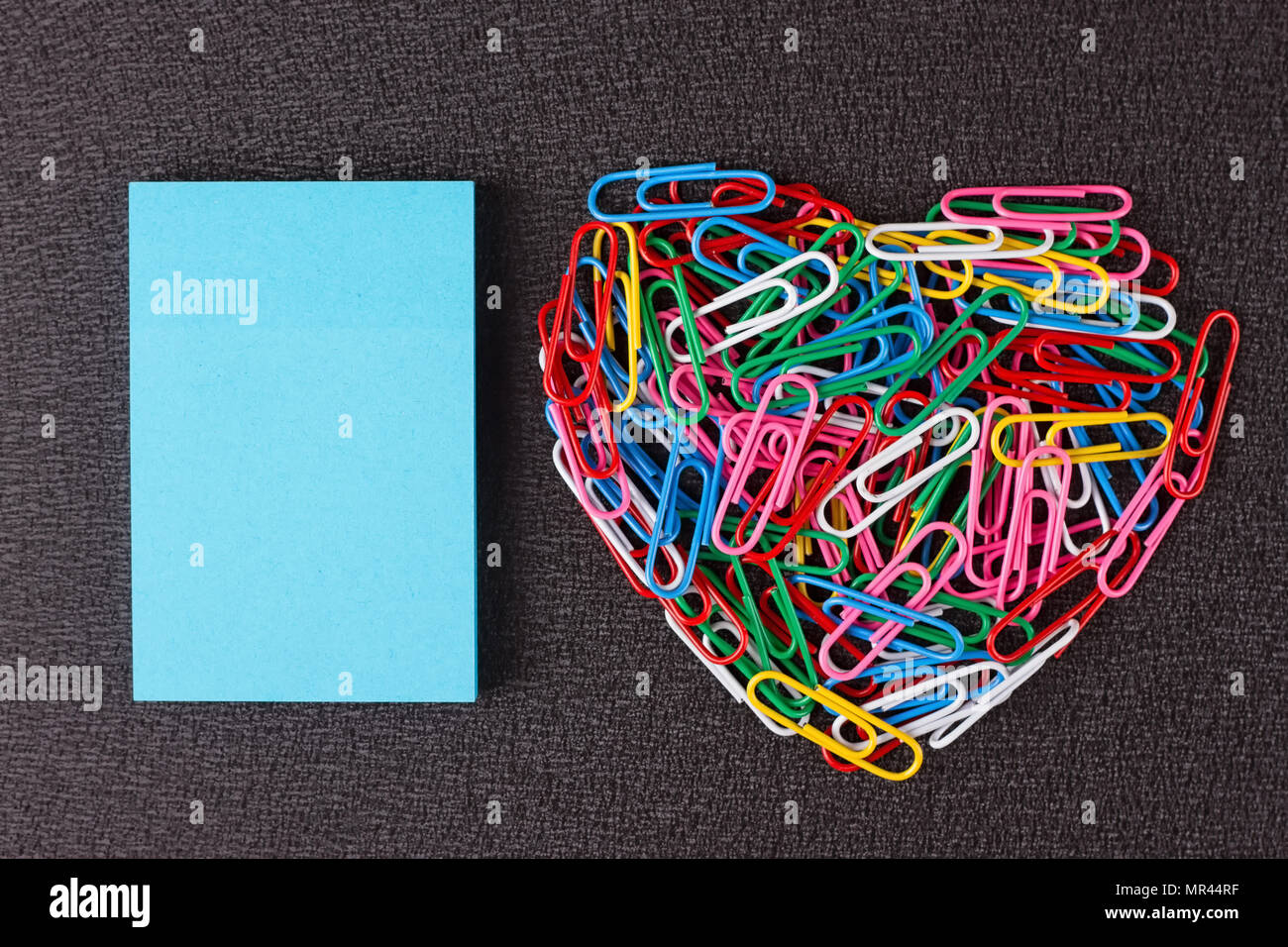 Variety of color paper clips arranged in heart shape on black ...