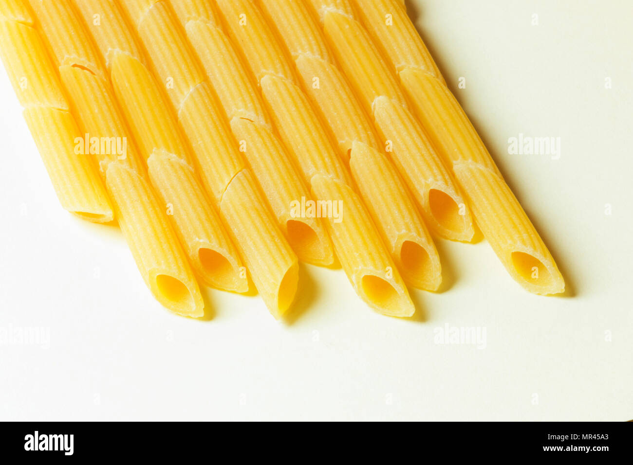 A layer of penne italian pasta lined on a white background ,top view ...