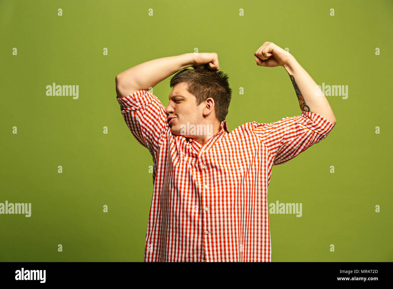 Handsome young man showing biceps expressing strength and gym concept ...