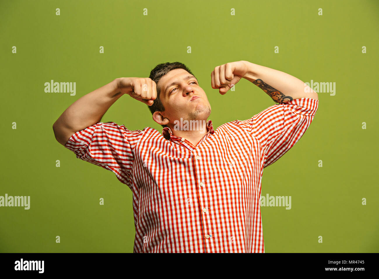 Handsome young man showing biceps expressing strength and gym concept ...