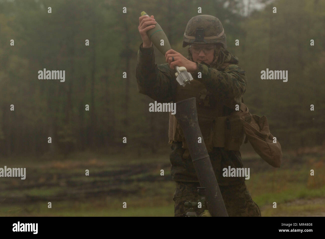 A Marine prepares to drop an 81mm mortar round into an M252 medium ...