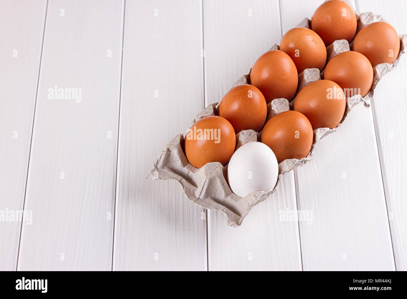 Container of ten eggs. Nine eggs brown one egg white. on white ...