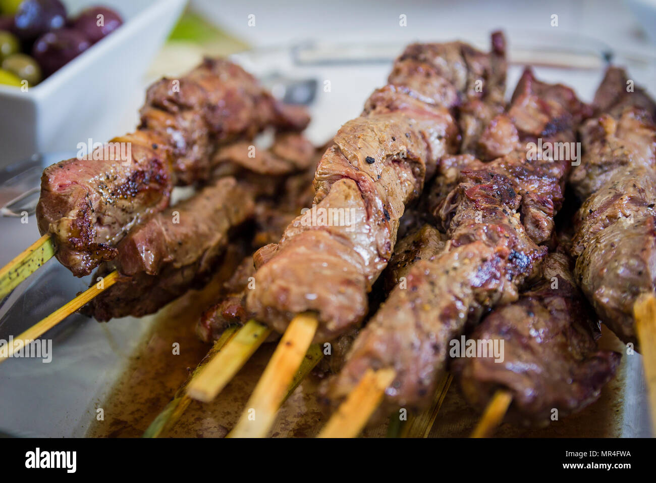 Close up on shashlik (lamb) meat with wooden skewer that is on white ...