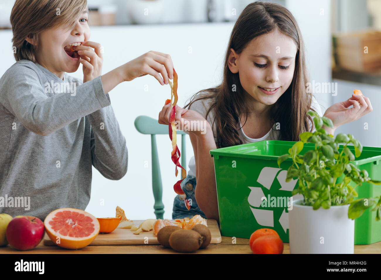 Kids playing with an apple skin while segregating waste in the kitchen ...