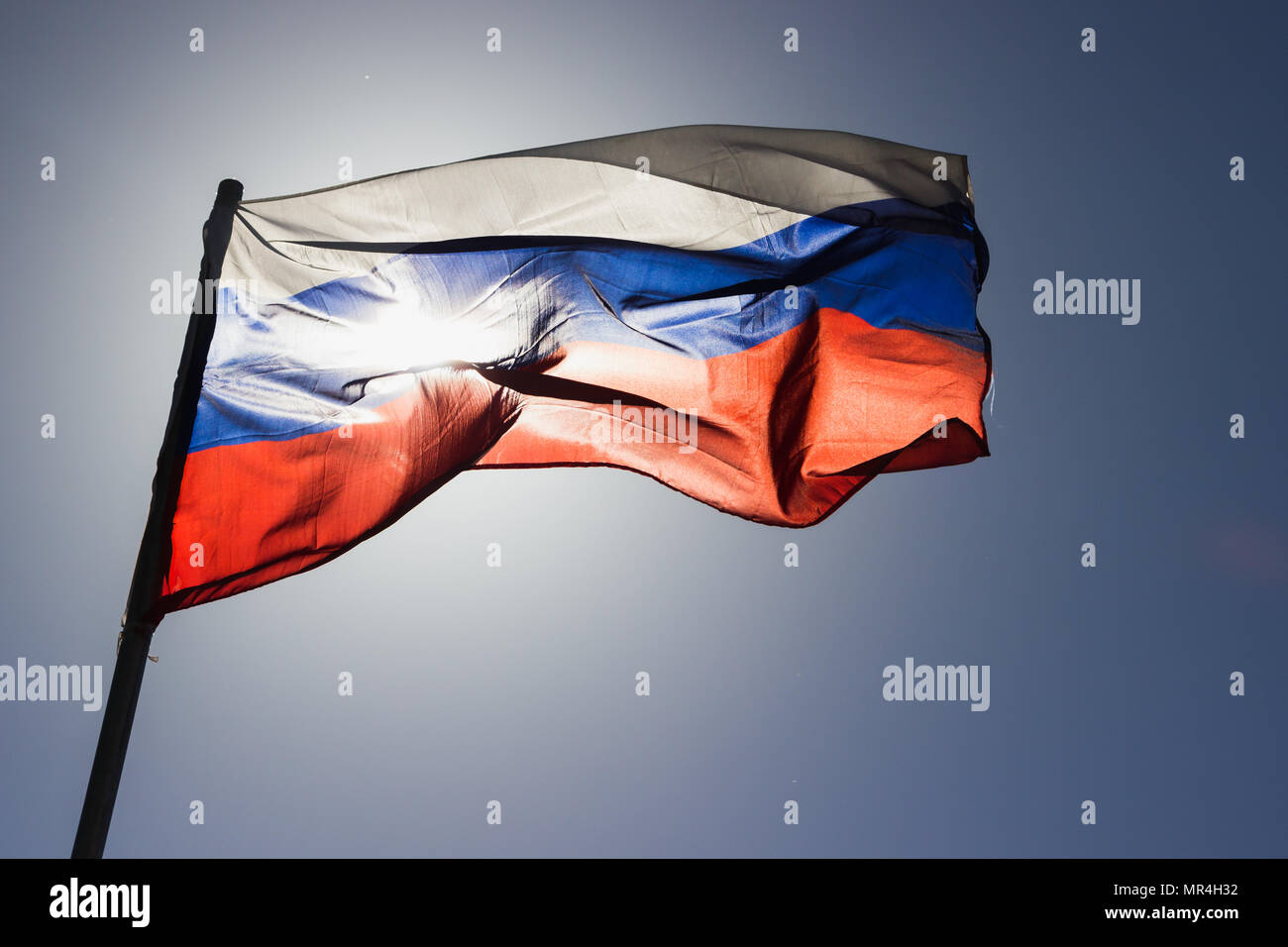 russian tricolor flag flying in slow motion and back lit by the sun ...