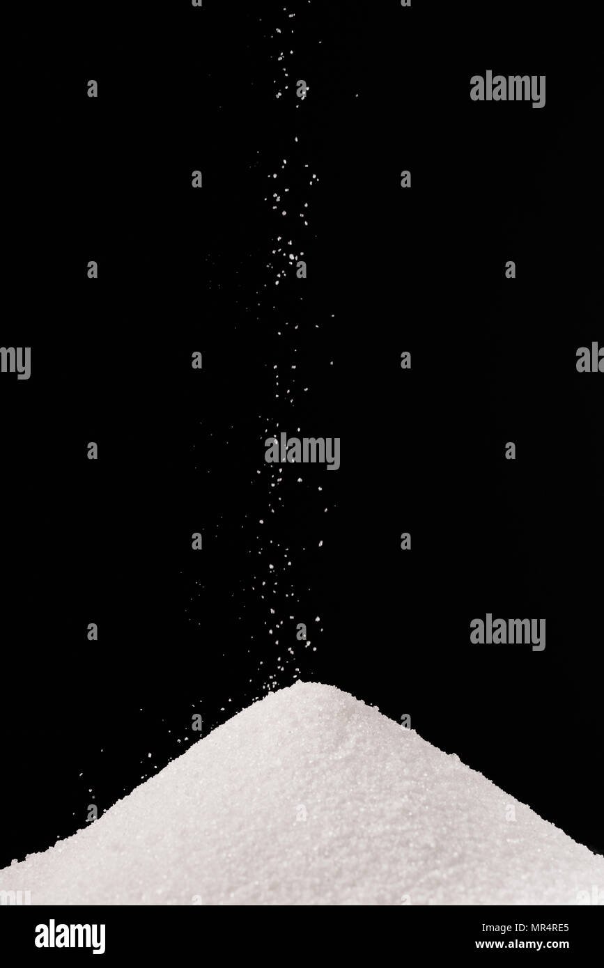 white sugar falling on pile isolated on black Stock Photo - Alamy
