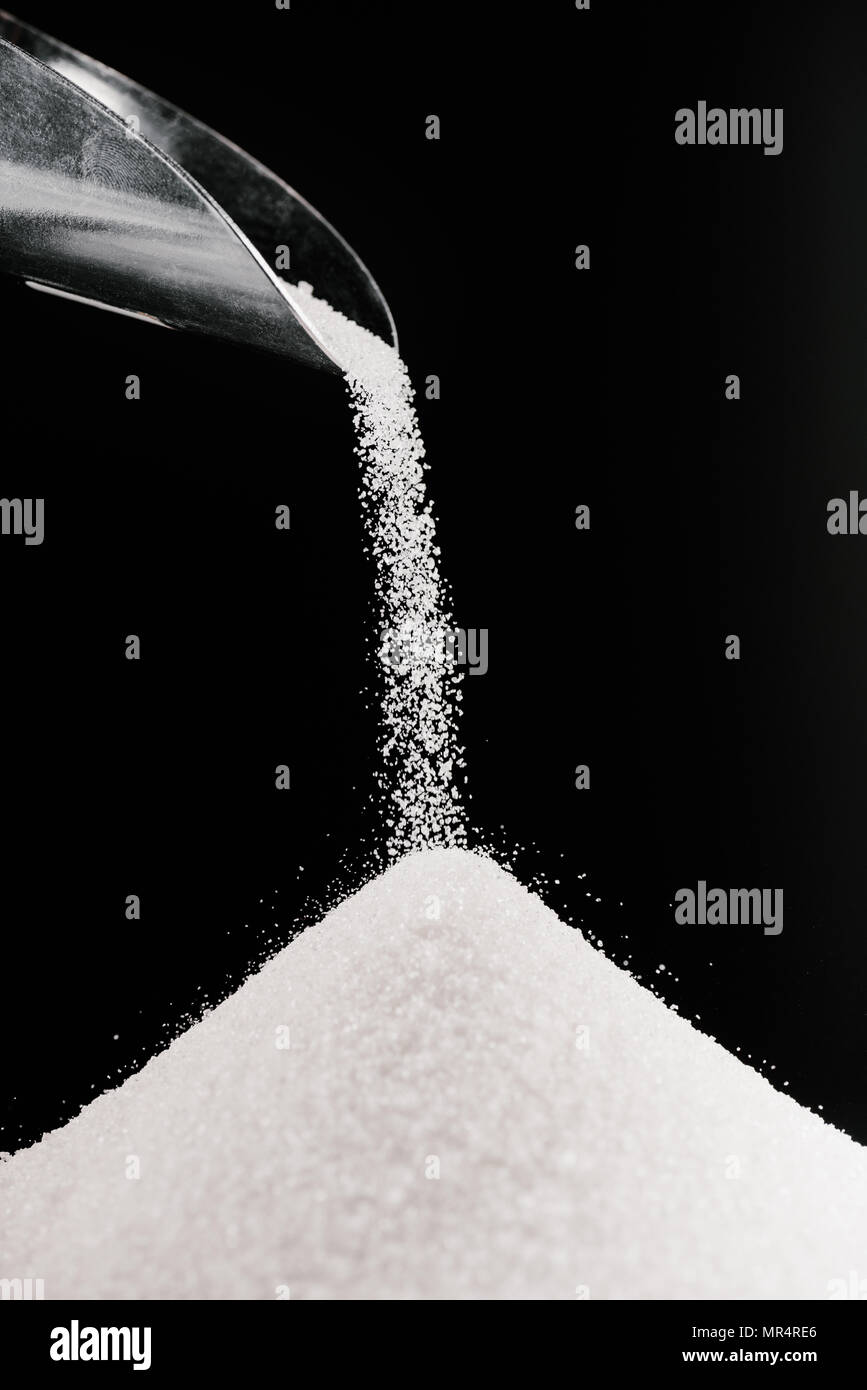 white sugar falling from metal scoop on pile isolated on black Stock ...