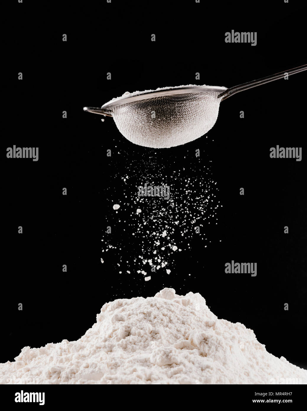 flour falling from sieve on pile for pastry isolated on black Stock ...