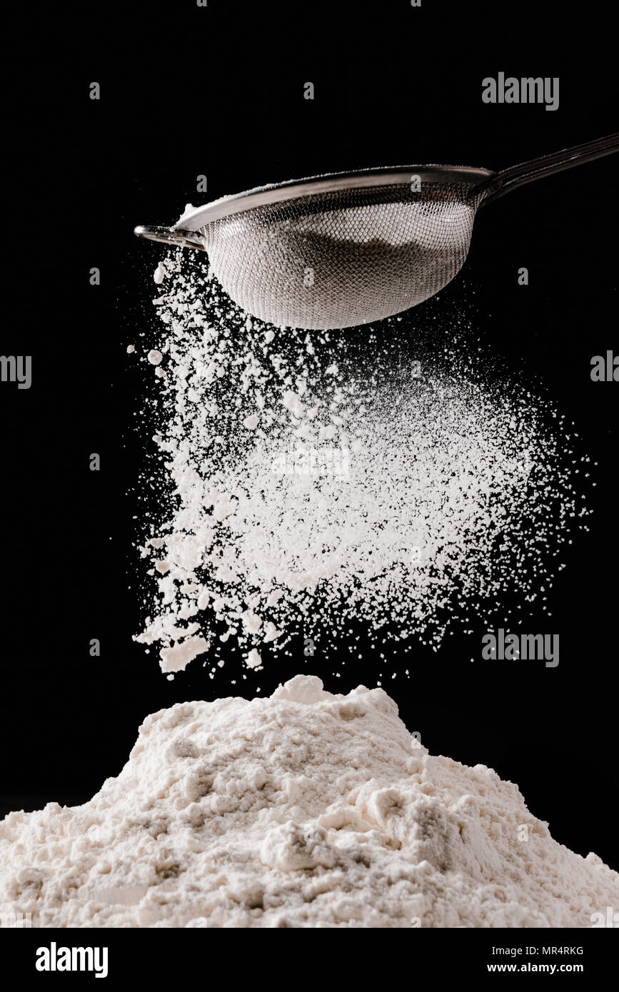 flour falling from sieve on pile isolated on black Stock Photo - Alamy