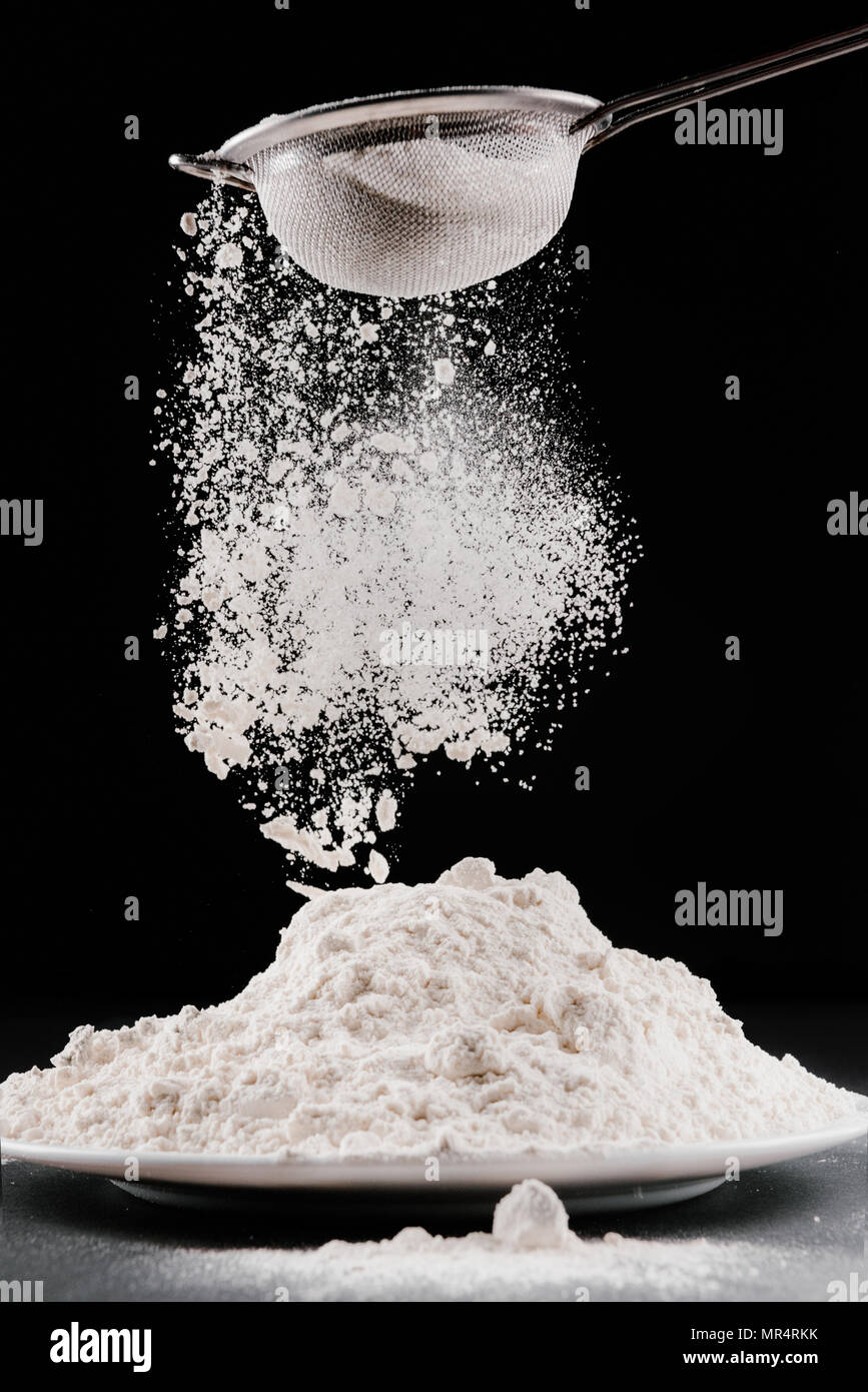 flour falling from sieve on pile isolated on black Stock Photo - Alamy