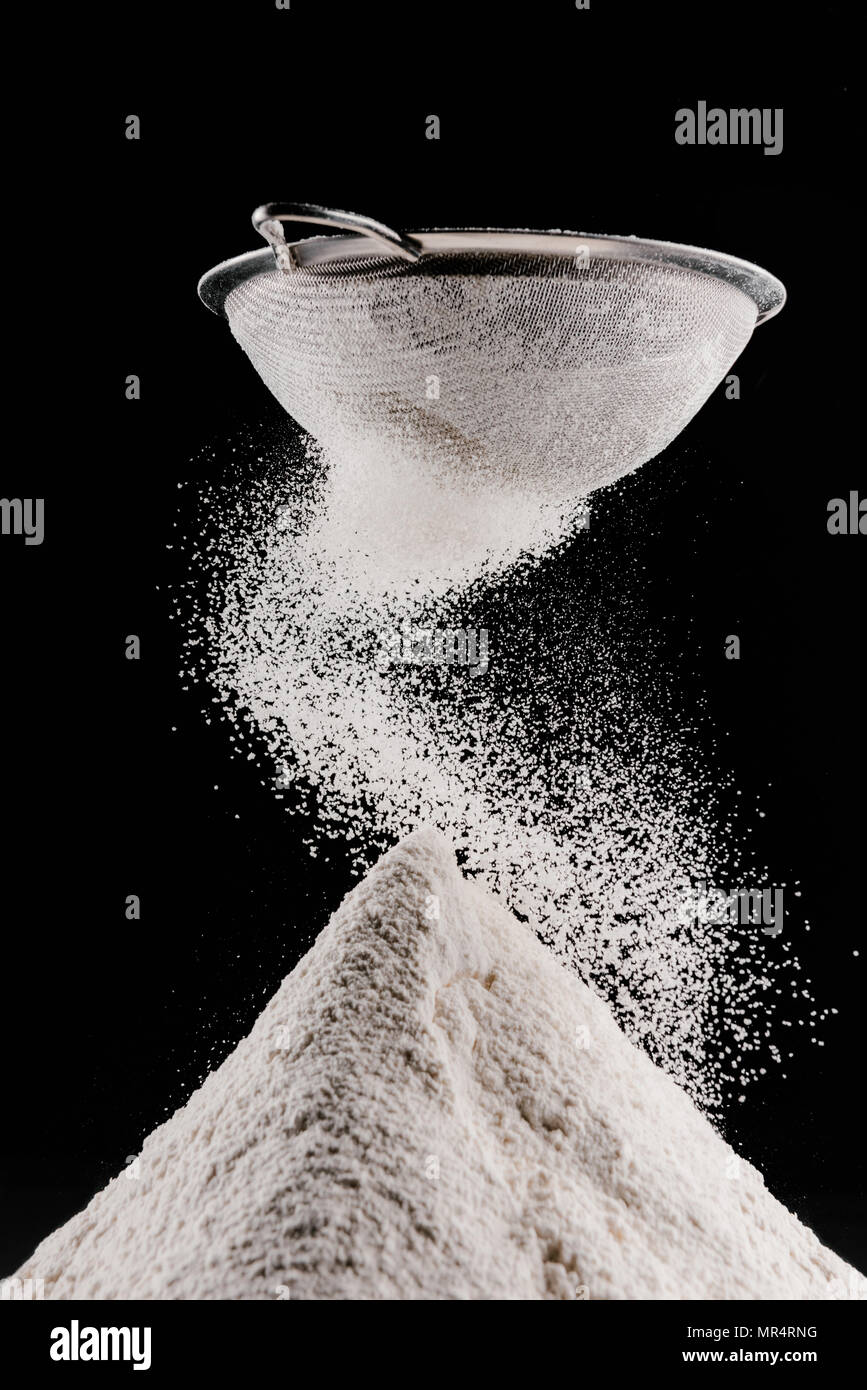 flour falling after sieving on pile isolated on black Stock Photo - Alamy