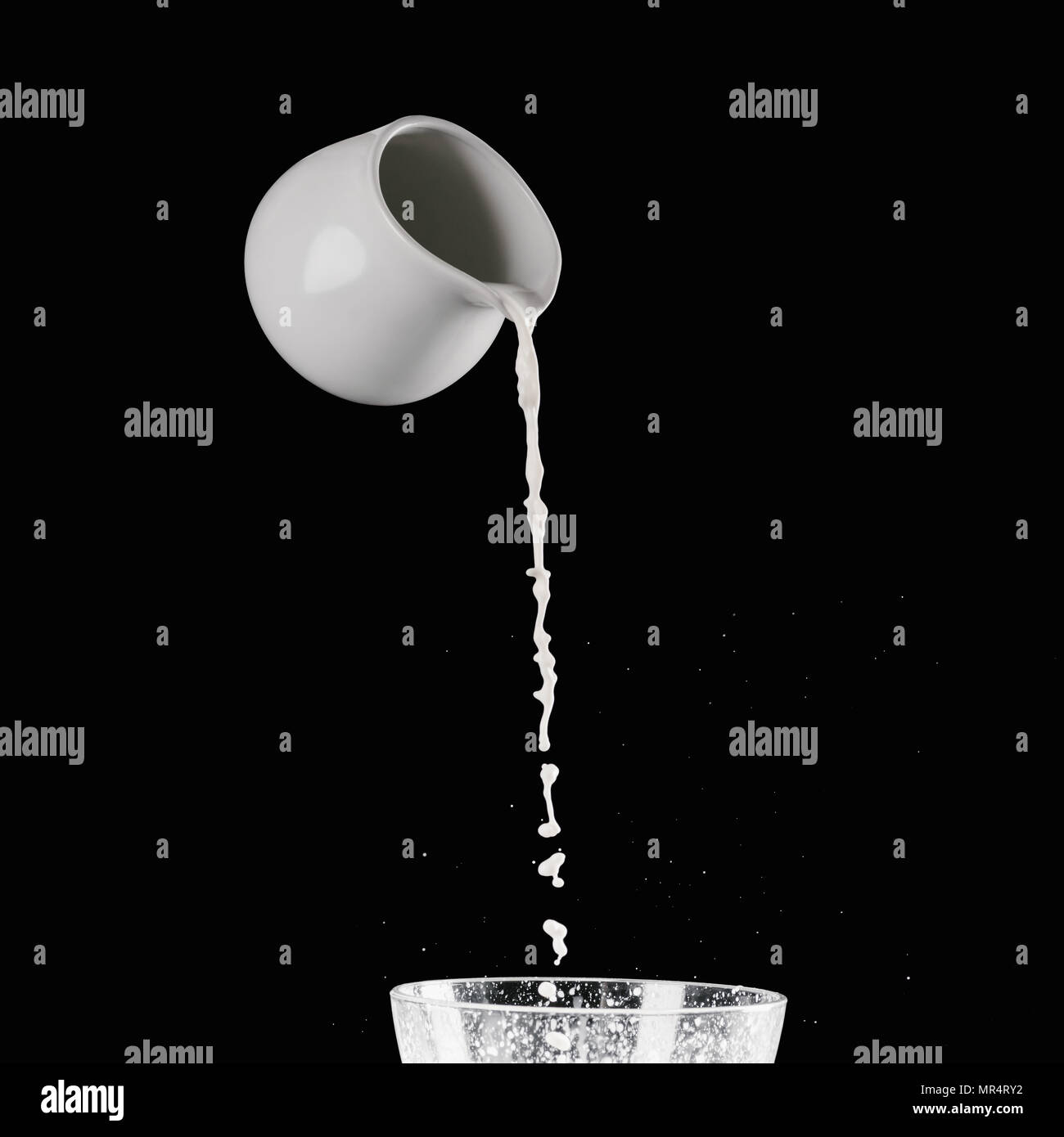 milk pouring from milk jar into bowl with flour isolated on black Stock ...