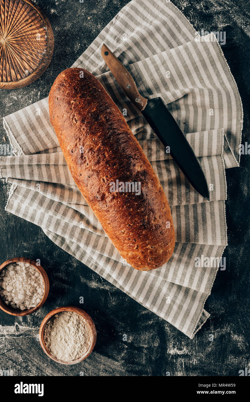 flat lay with loaf of bread on linen and bowls with flour near by on ...