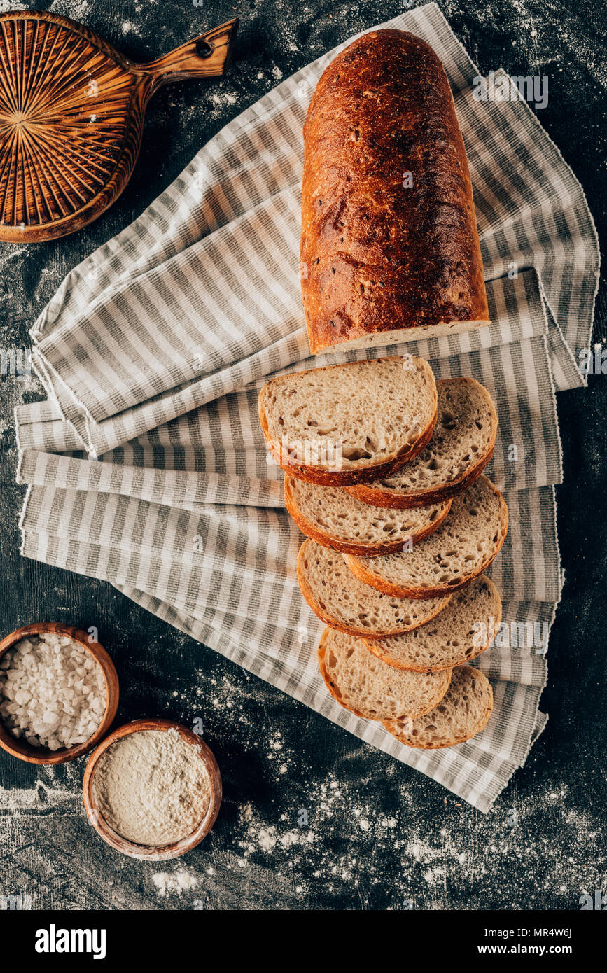 flat lay with pieces of bread on linen and bowls with flour near by on ...