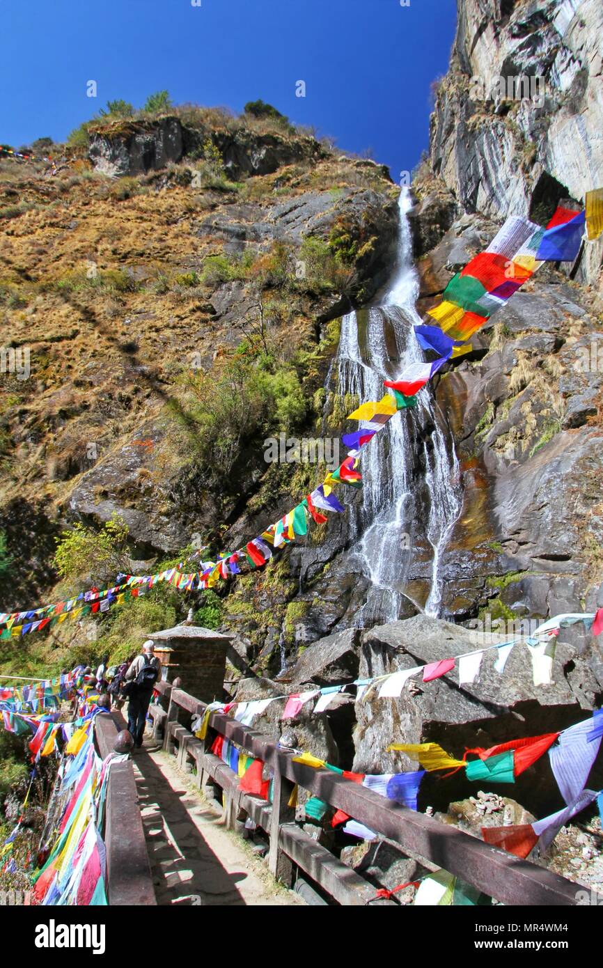 Holy waterfall with colorful Buddhist prayer flags at Taktshang Goemba ...