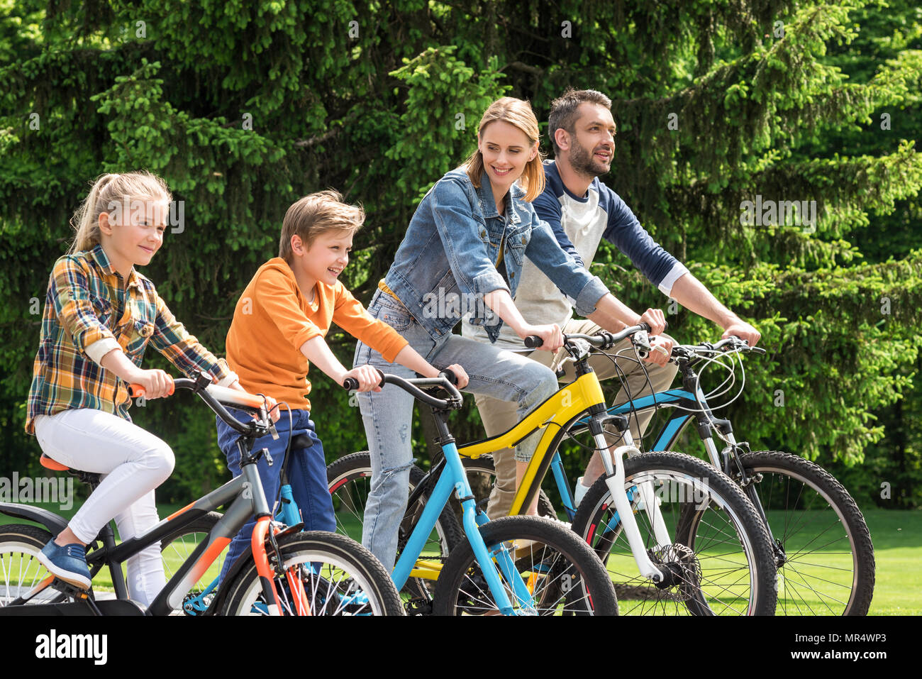 side view of happy family riding bicycles together in park Stock Photo ...
