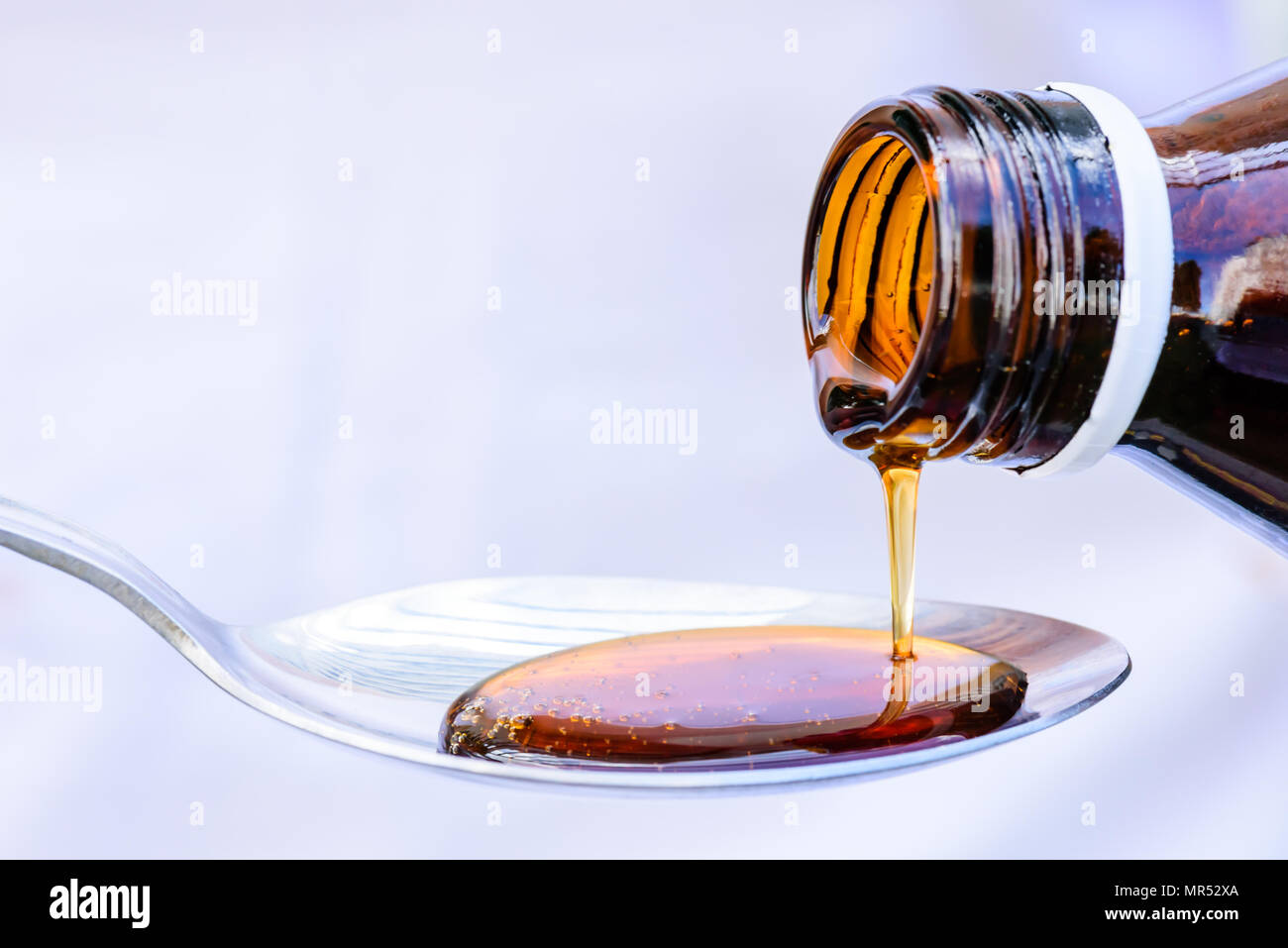 Hand pouring medication or antipyretic syrup from bottle to spoon ...