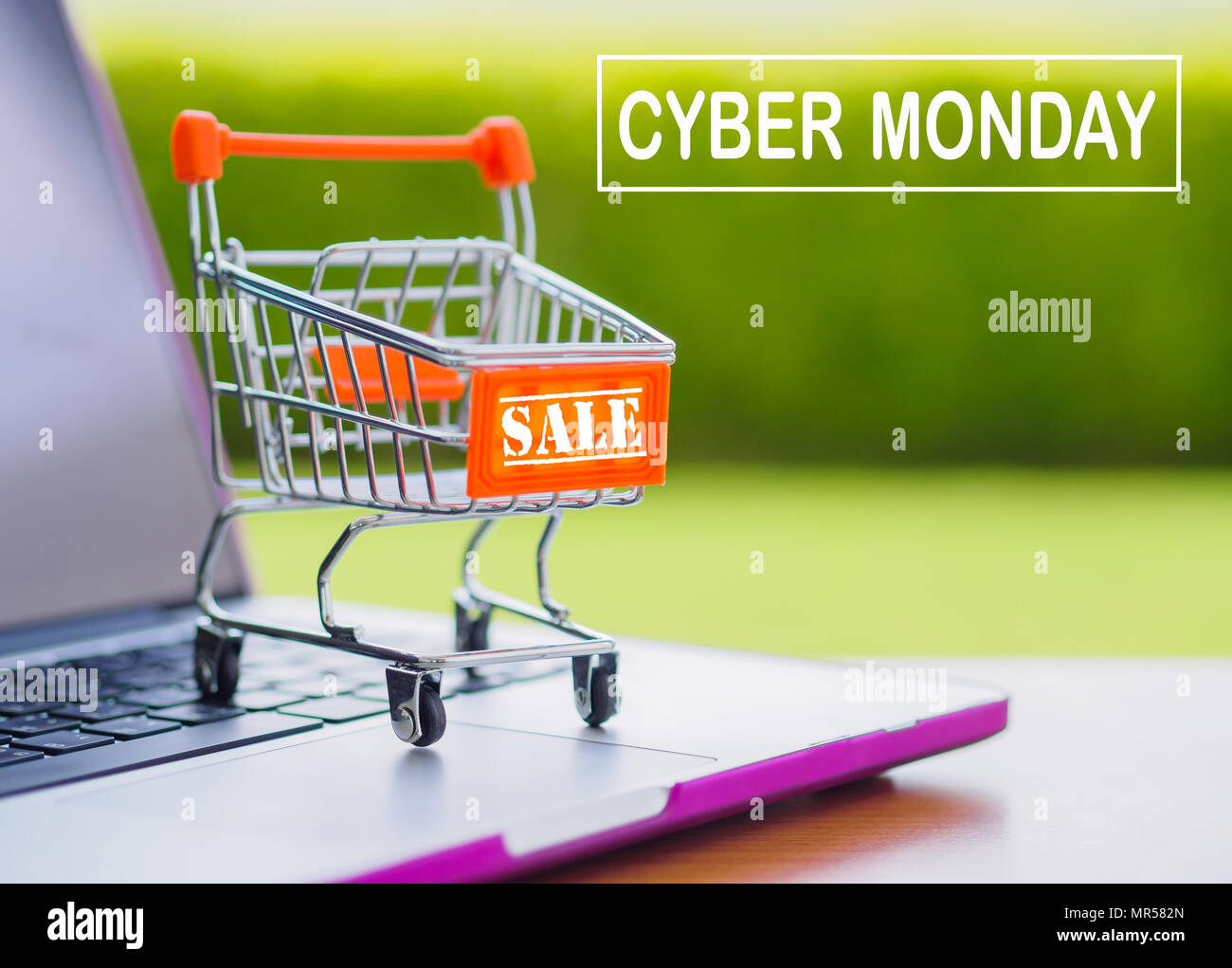 Cyber Monday shopping concept : mini shopping cart on laptop with green ...