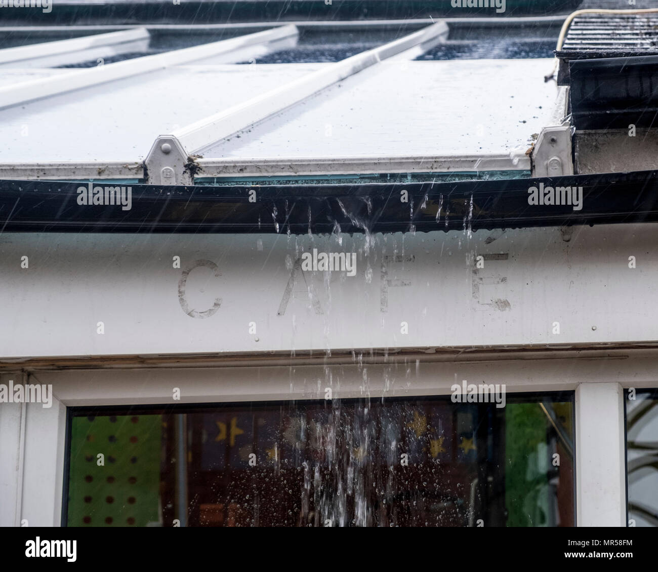 Wet weather. Heavy rain pouring down a roof and out of a gutter ...