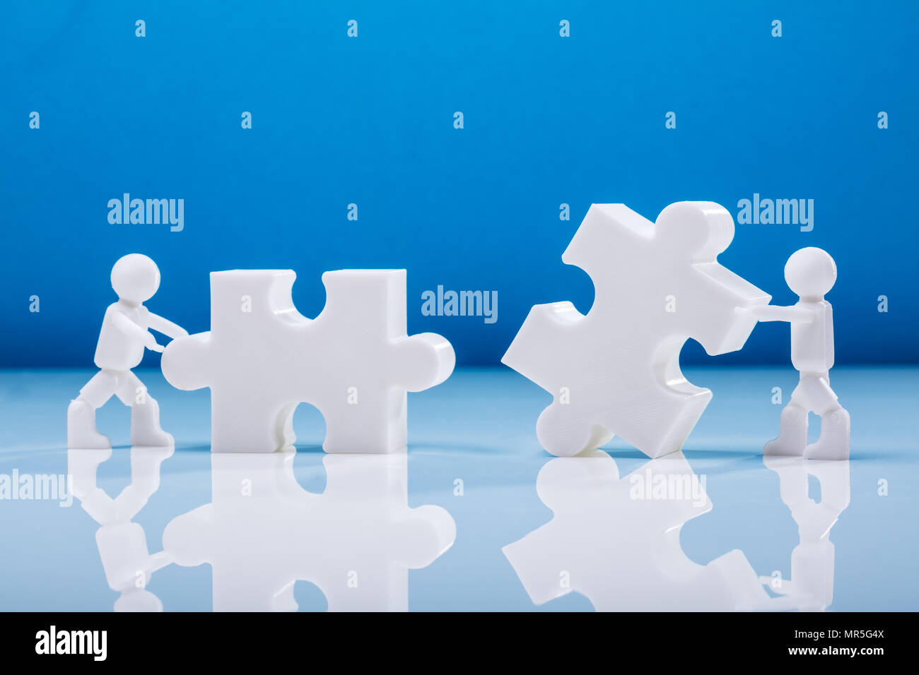 Two Human Figures Solving Jigsaw Puzzle Against Blue Background Stock ...