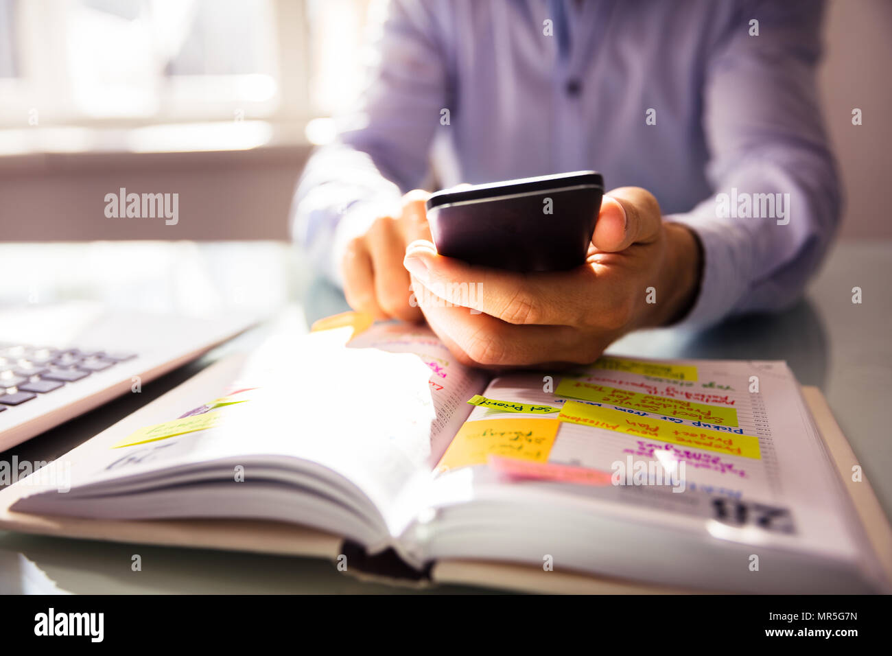 Businessperson Using Mobile Phone With Diary On Desk Stock Photo - Alamy
