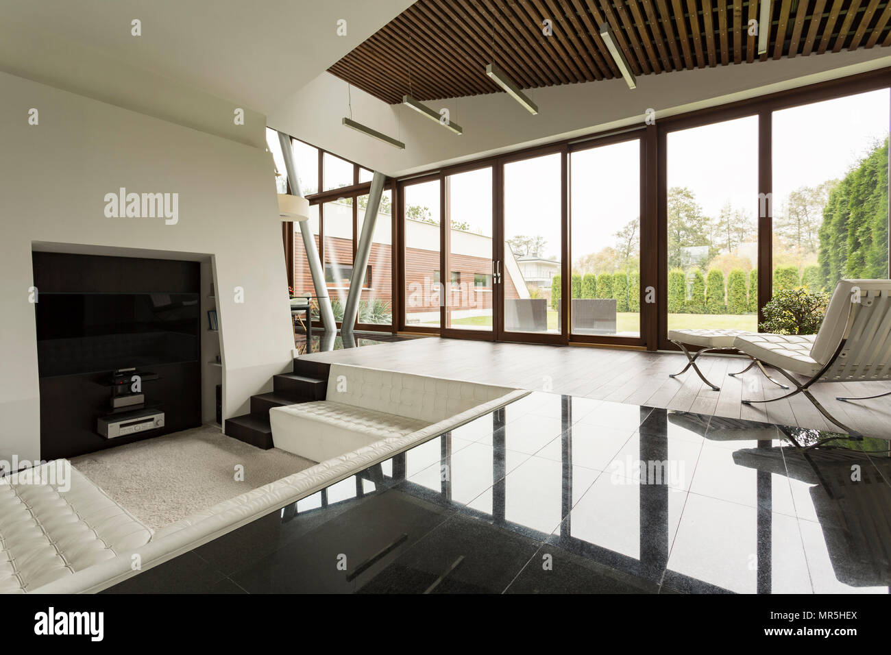 Bright villa interior with wood ceiling, black floor and tv Stock Photo ...