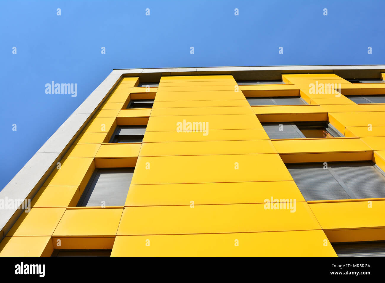 Yellow building with windows and blue sky Stock Photo - Alamy