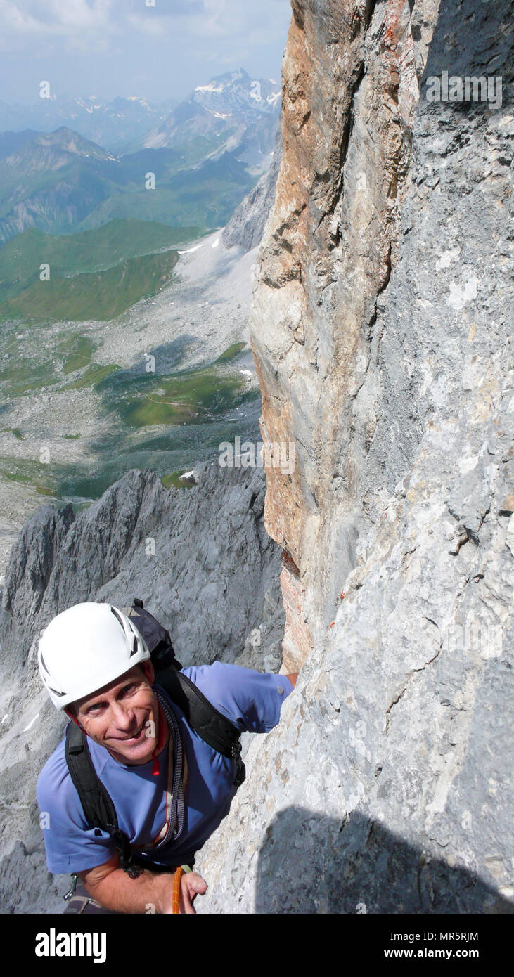 male mountain climber on a steep rock climbing route in the Swiss Alps ...