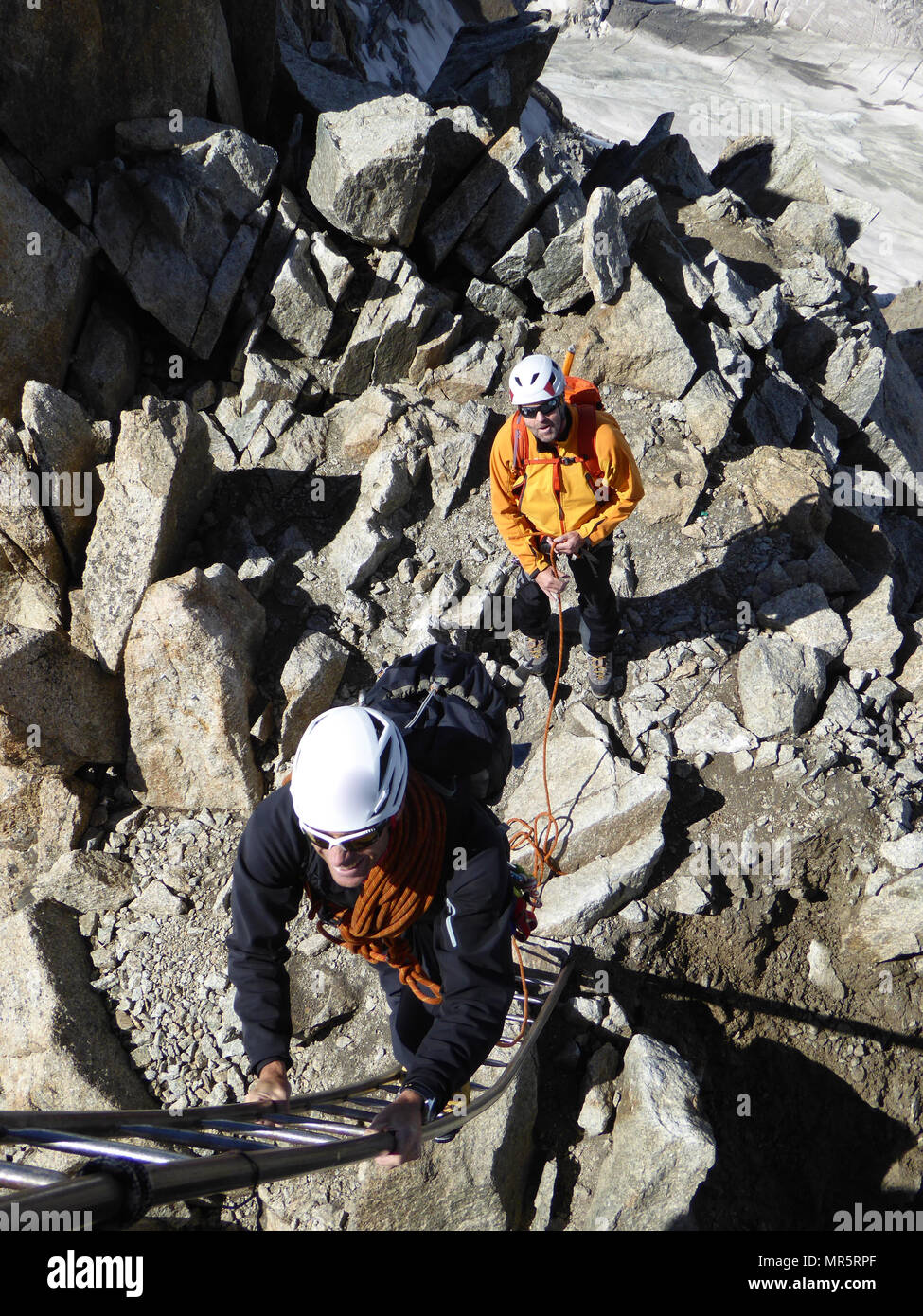 mountain guide and client get ready to climb a ladder to the exit of ...