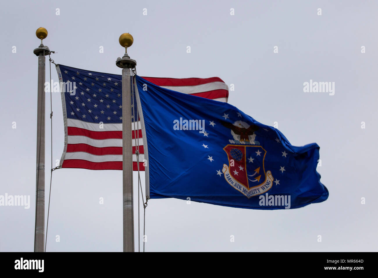 The American and 514th Air Mobility Wing flags fly in front of the Wing ...