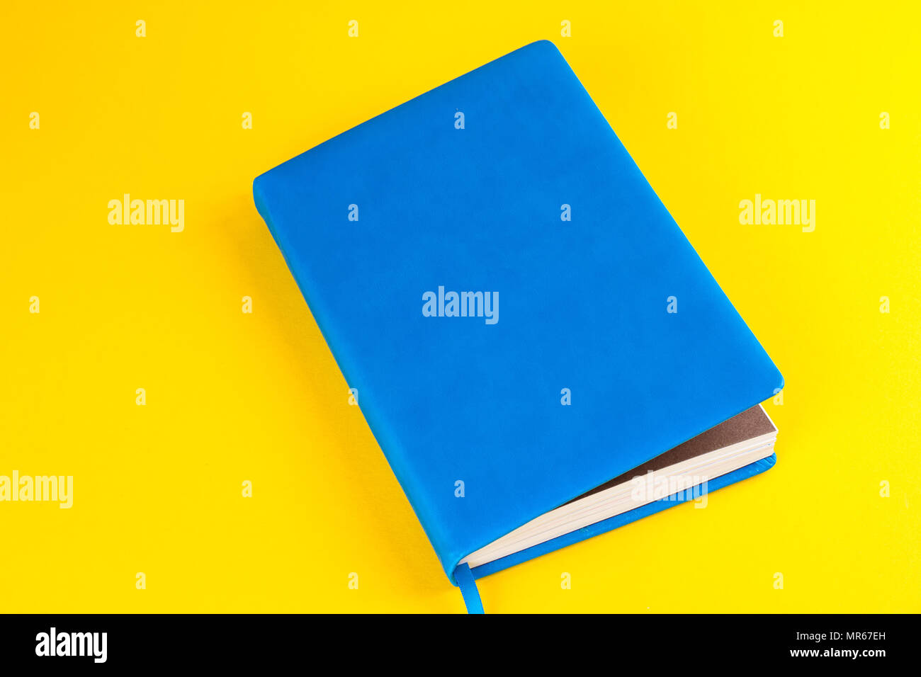 Blue closed diary on a yellow background Stock Photo - Alamy