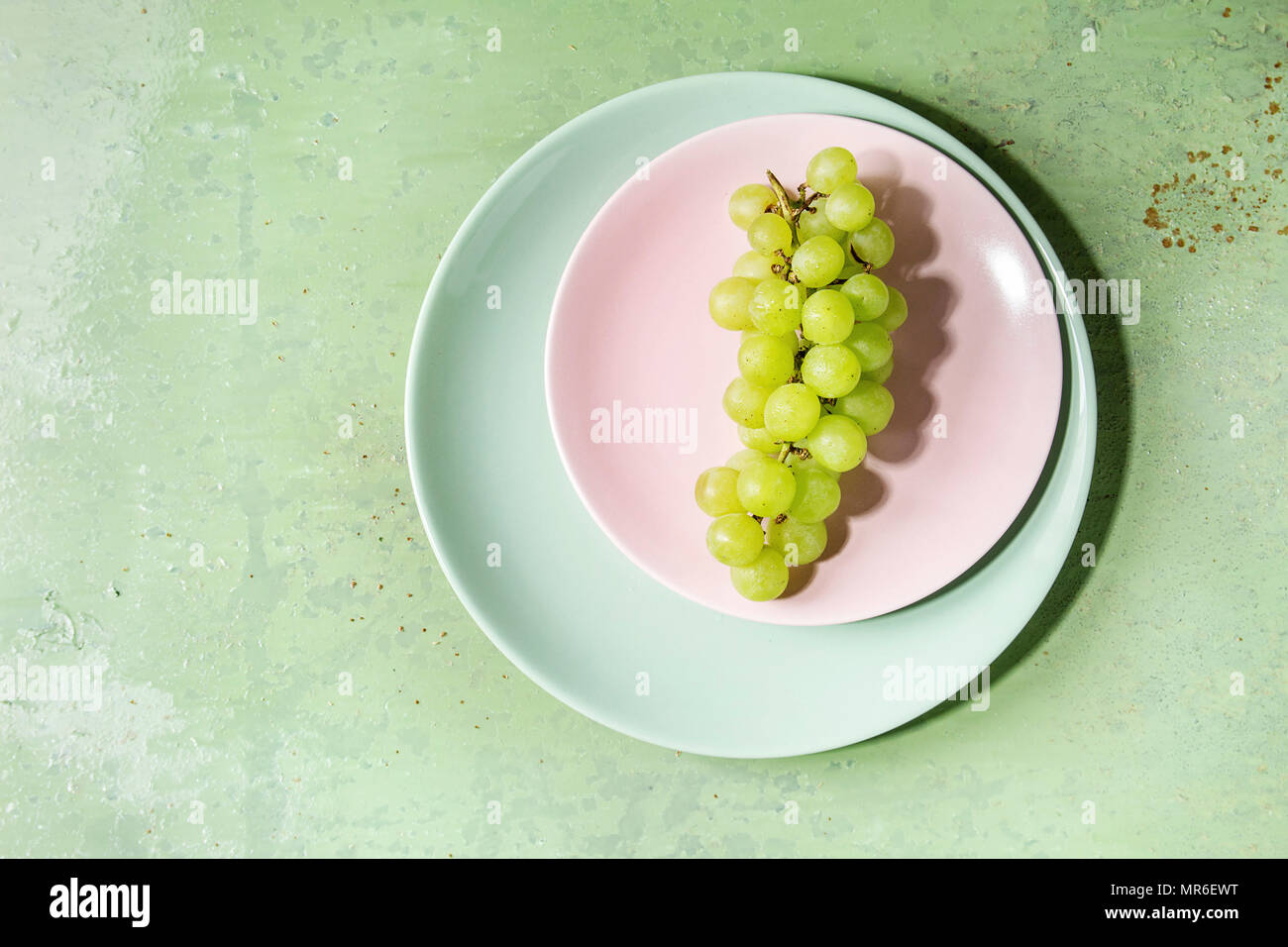 Bunch of ripe green grapes on turquoise plate over green pastel pin-up ...