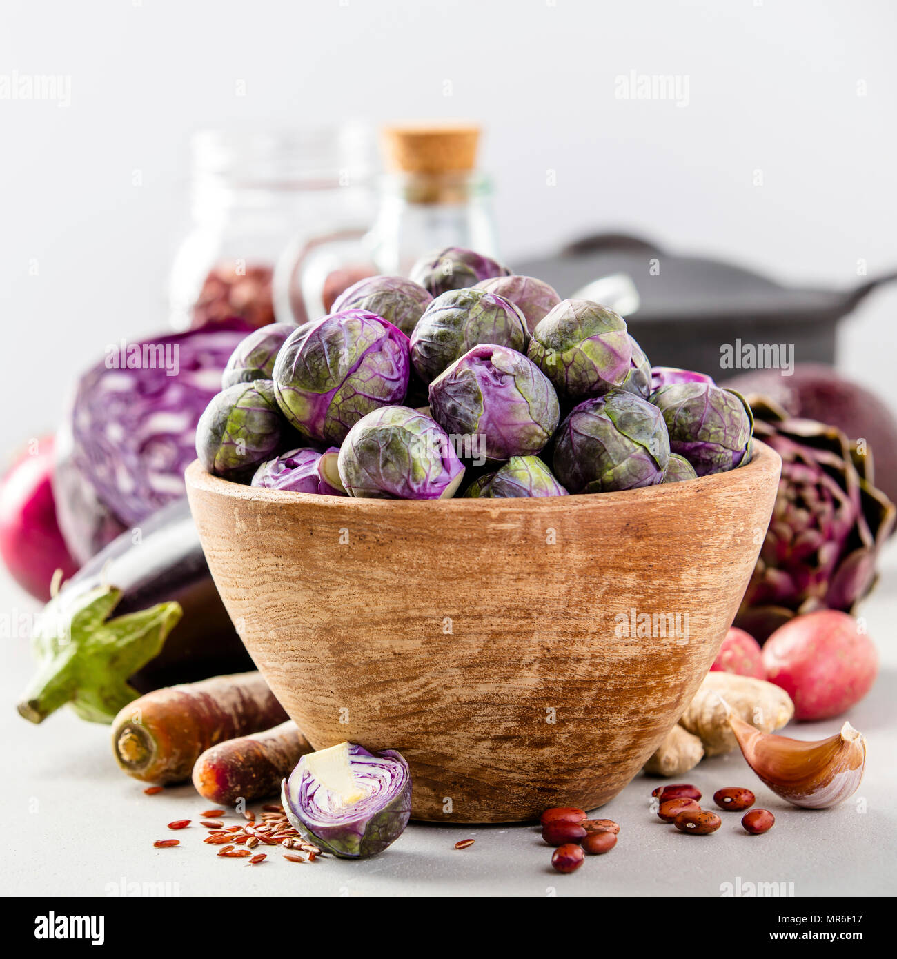 Purple Brussels sprouts in a bowl and healthy ingredients on concrete ...