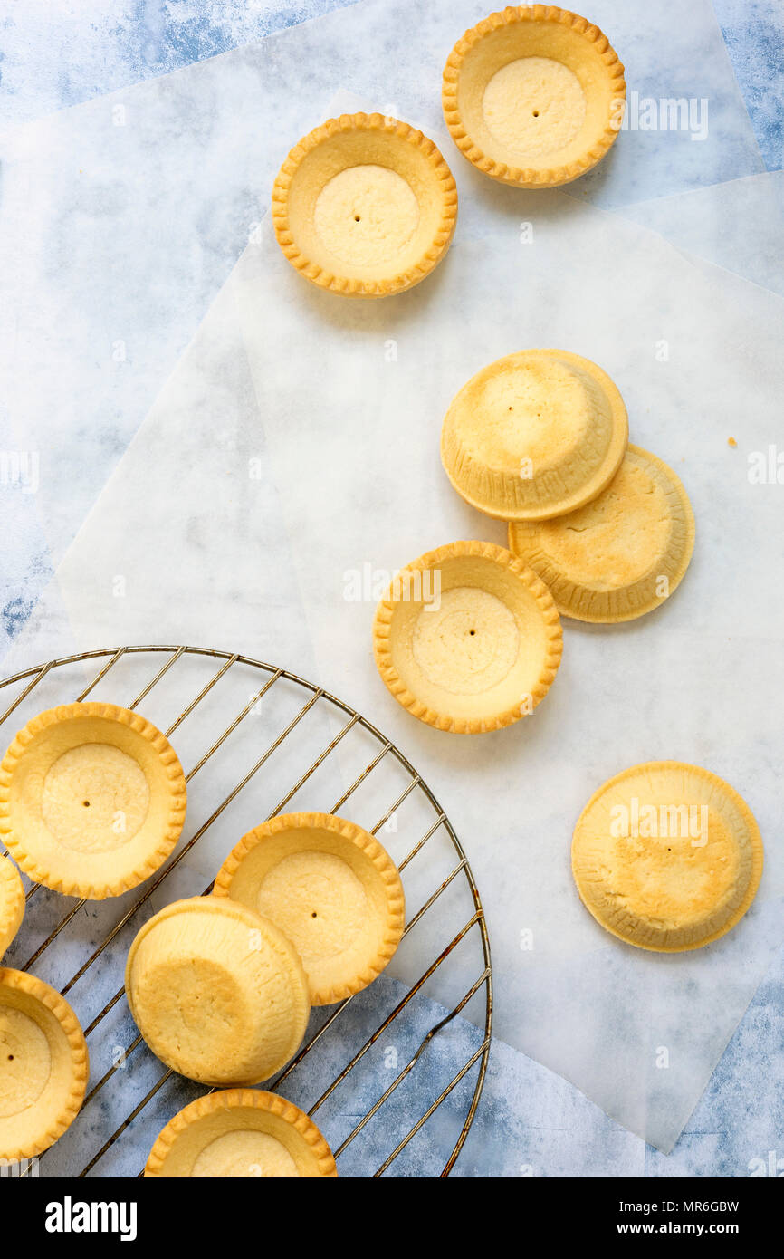 Small baked pastry tartlet cases cooling on a wire rack and baking ...