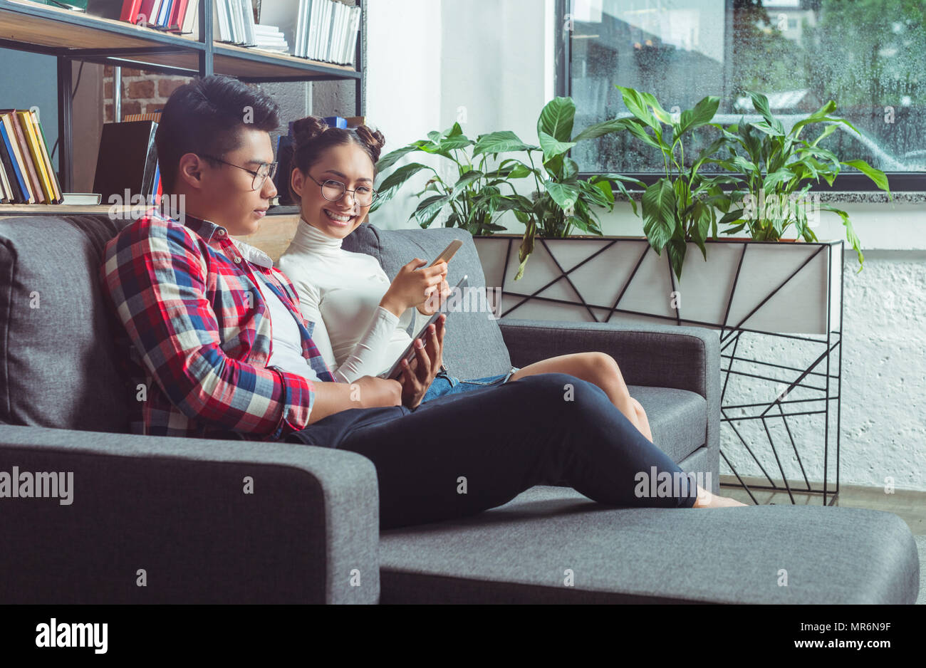 smiling young asian students using digital devices in library Stock ...