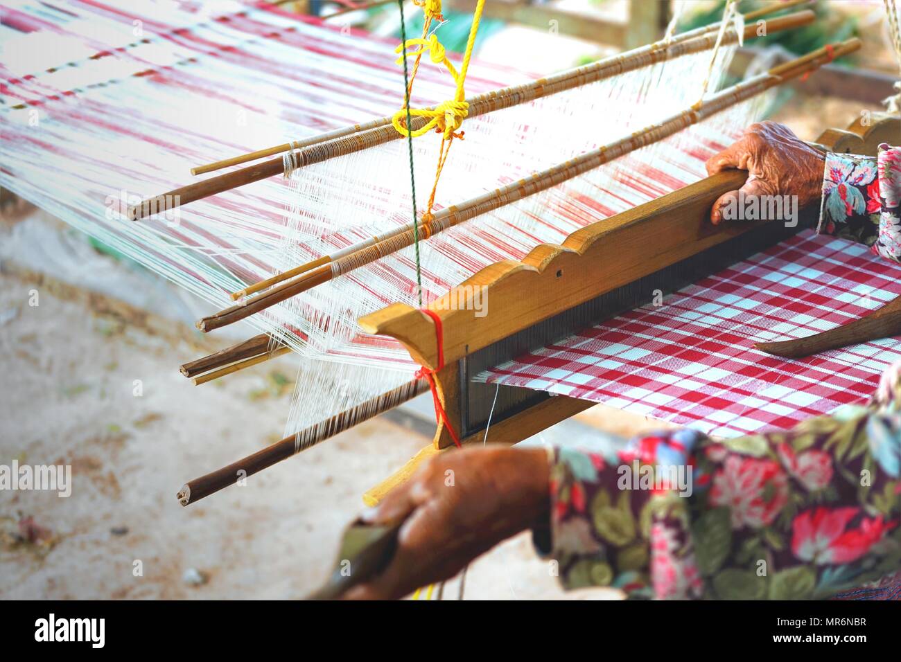 Hands of an old woman using traditional household weaving machine or ...